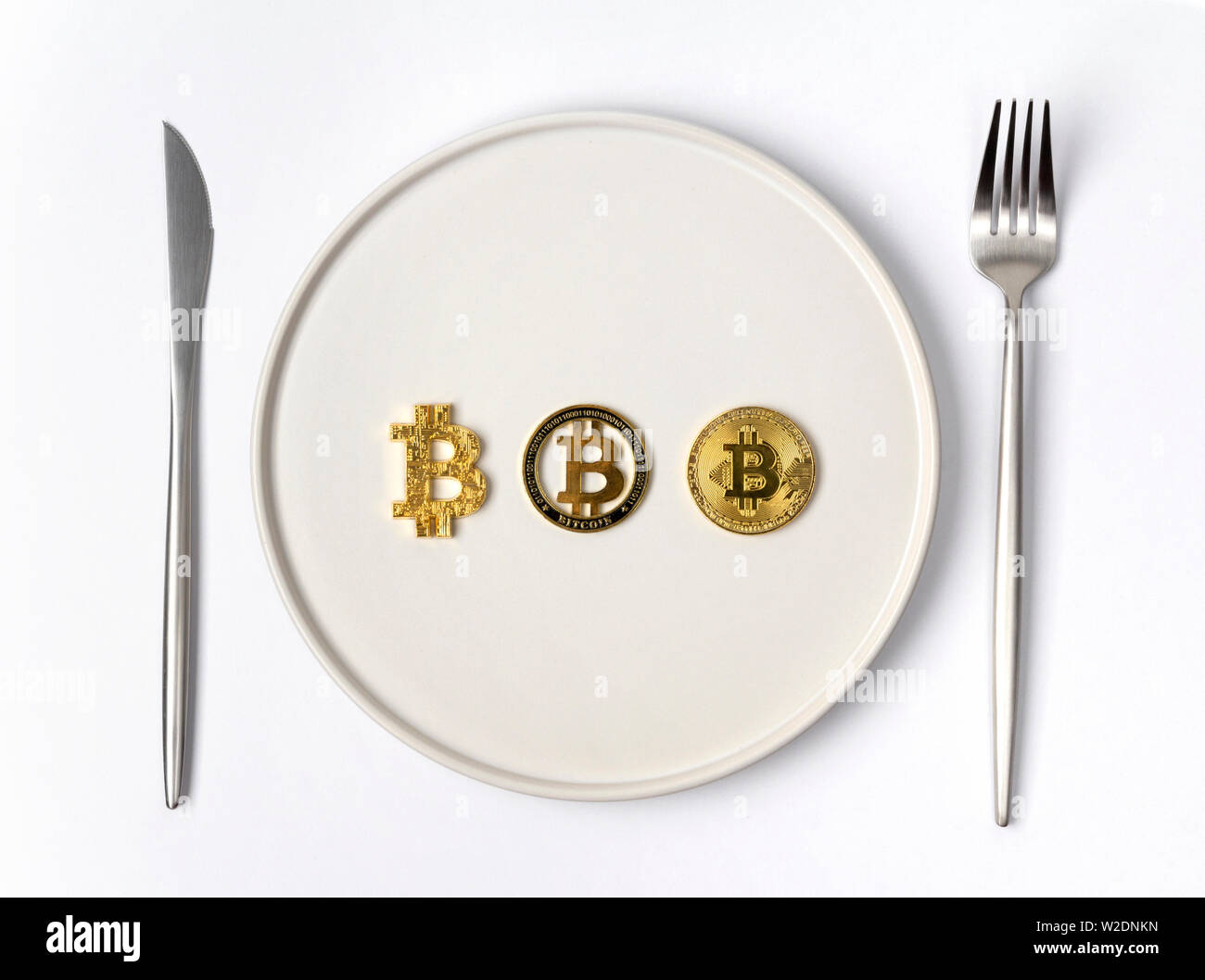 Three gold coins bitcoin served on white empty plate with fork and ...