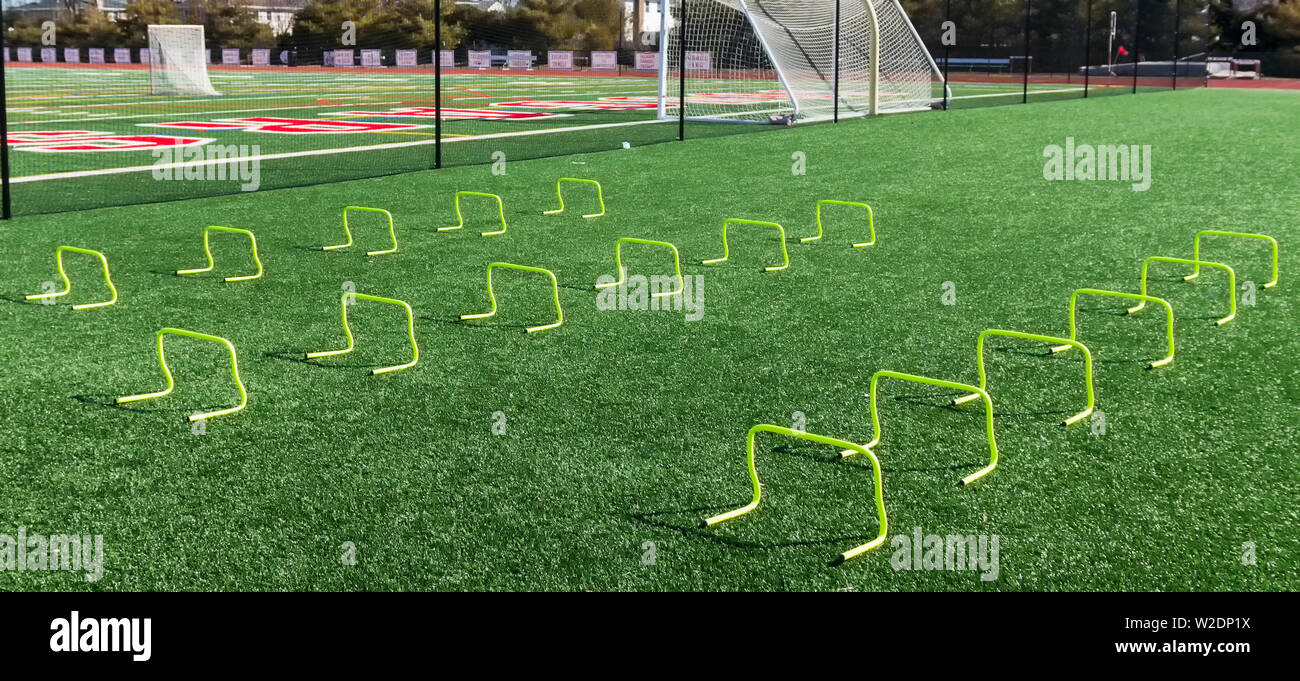 12 inch banana hurdles set up on a green turf field for speed training at track and field ...