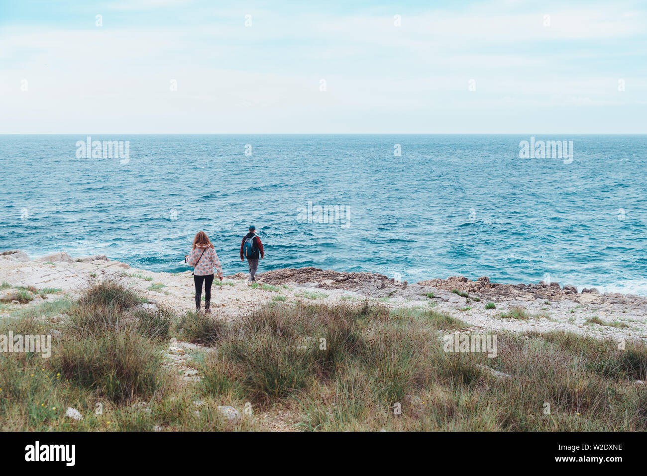 couple walking to sea. windy weather. not calm sea. waves. copy space ...