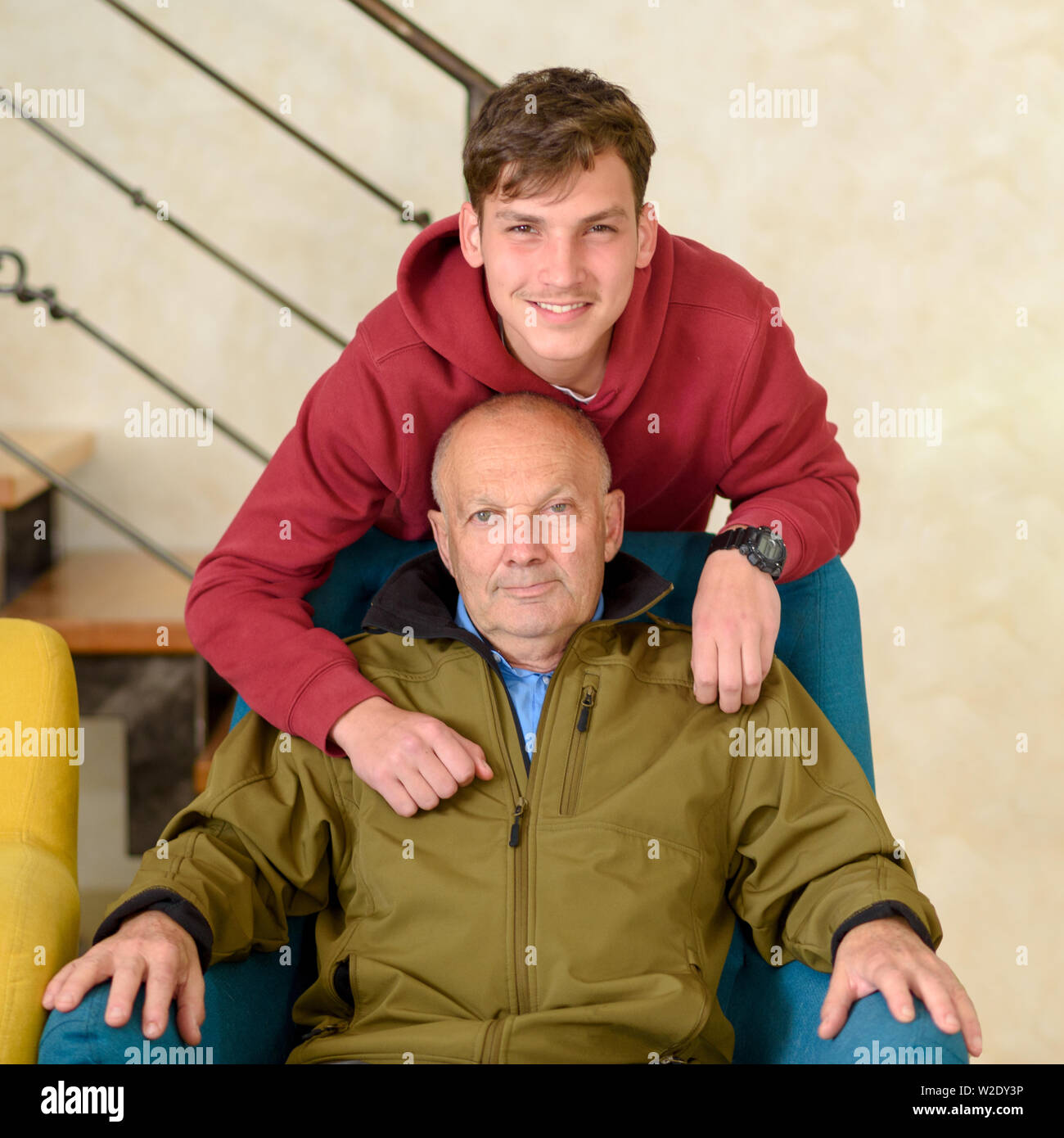 Senior father and young smiling son looking away in a home. Happy old ...