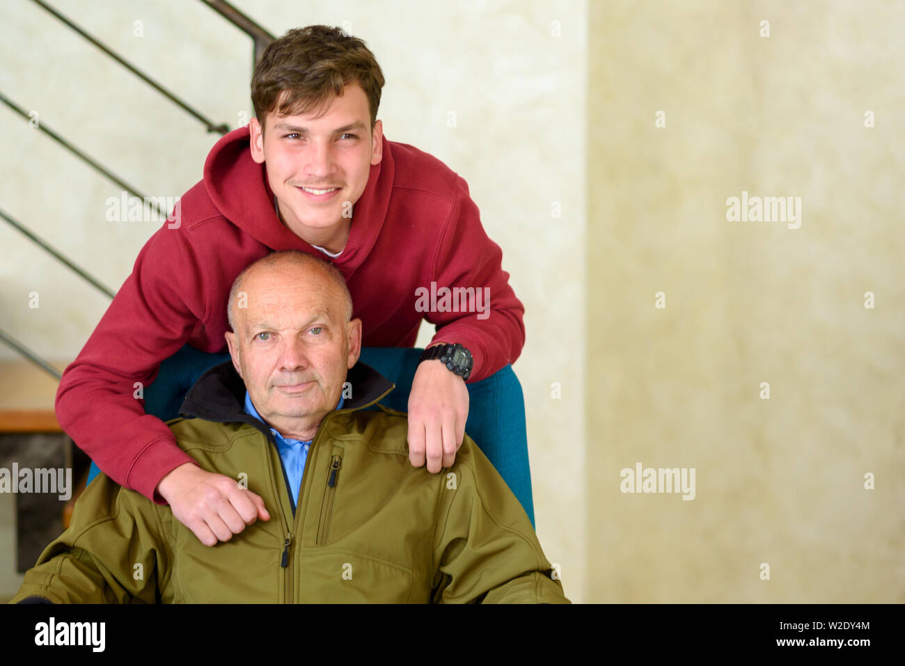Senior father and young smiling son looking away in a home. Happy old ...