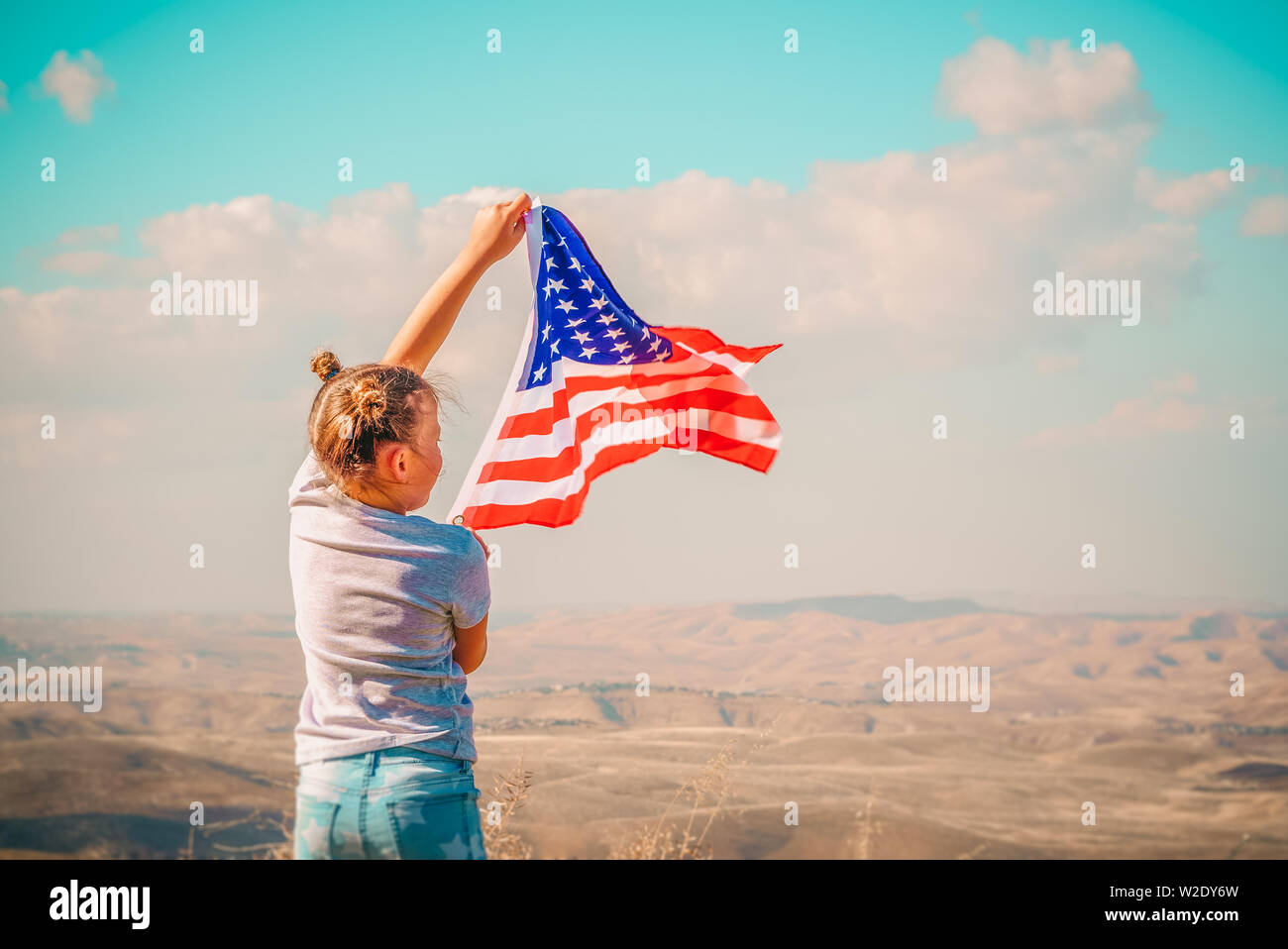 American flag. Back view little patriotic happy girl holding american ...