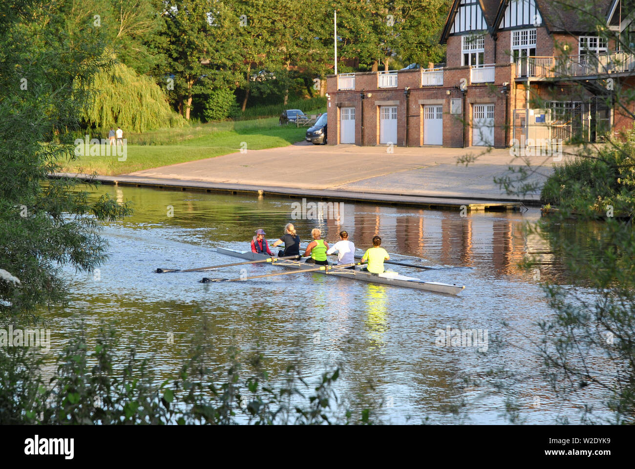 A row boat passing the Pengwern Boat Club building on the River Severn ...