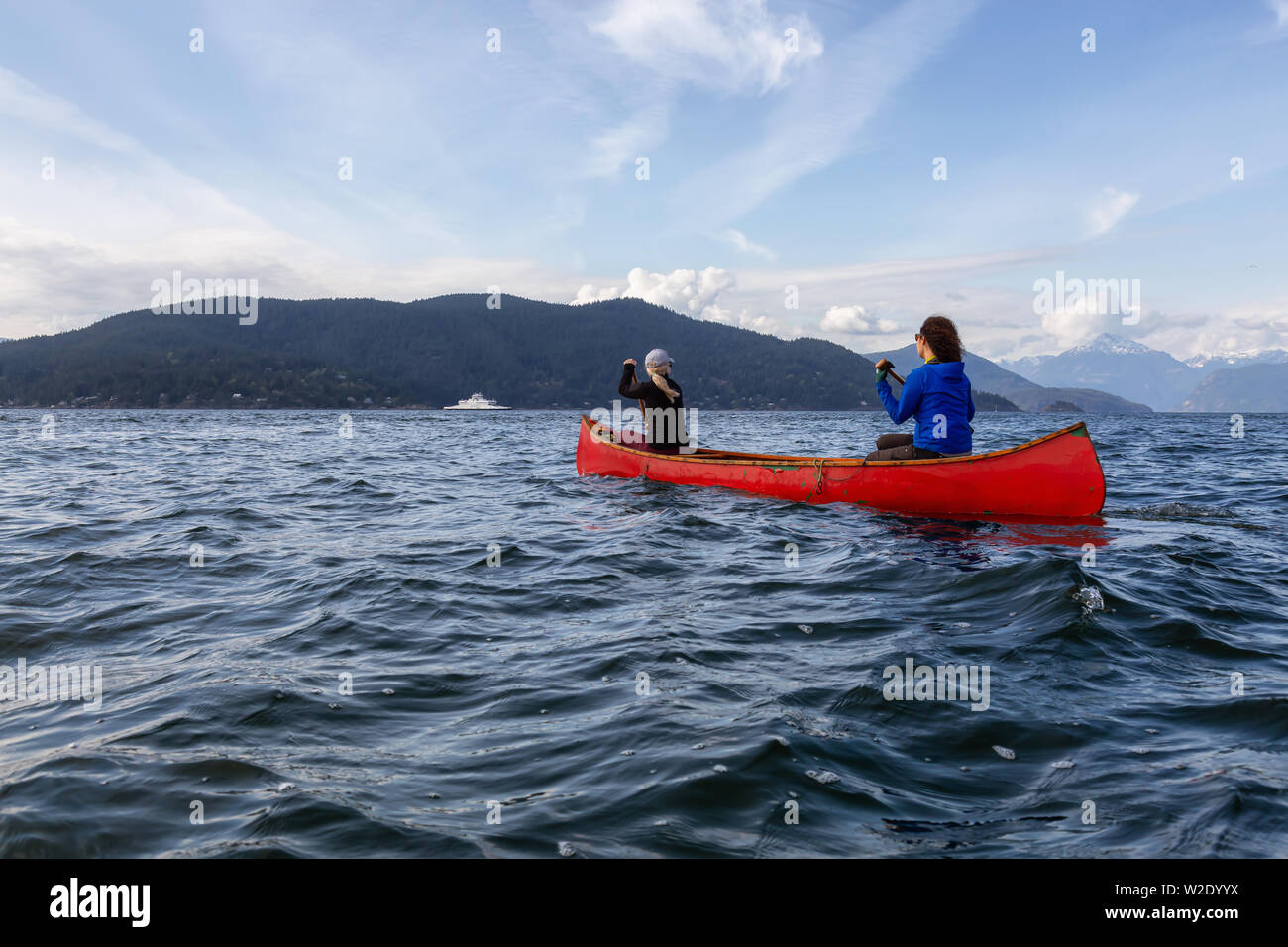 Couple adventurous female friends on a red canoe are paddling in the ...