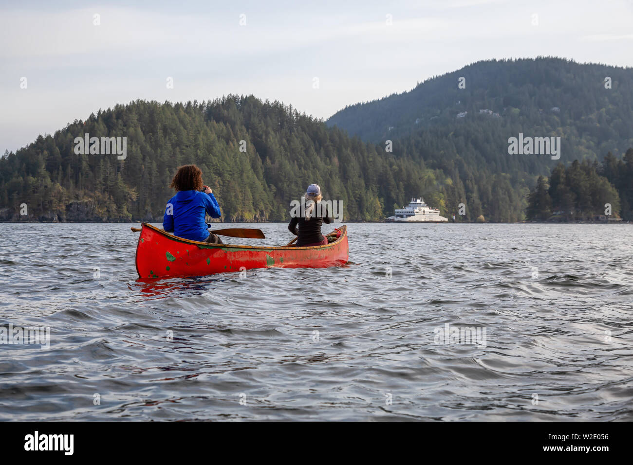 Couple adventurous female friends on a red canoe are paddling in the ...