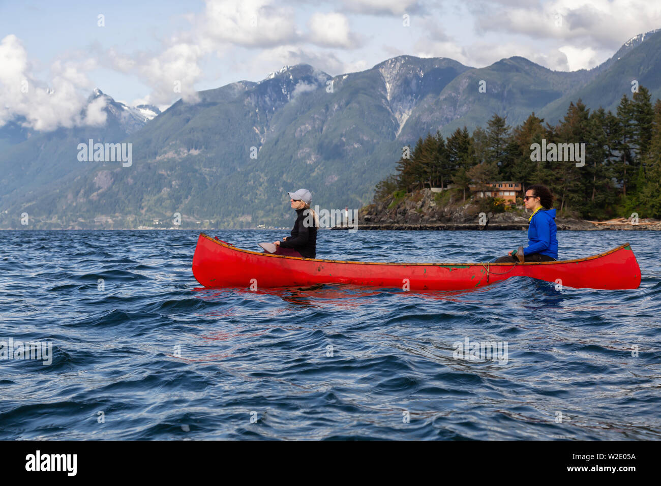 Couple adventurous female friends on a red canoe are paddling in the ...