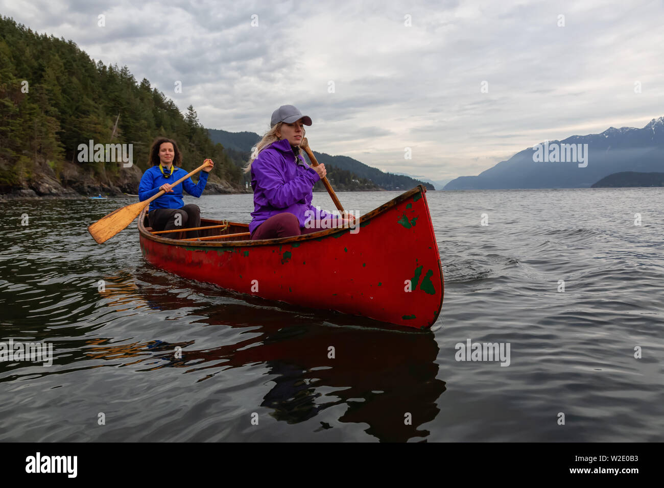 Couple adventurous female friends on a red canoe are paddling in the ...