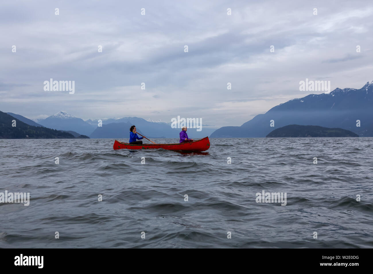 Couple adventurous female friends on a red canoe are paddling in the ...