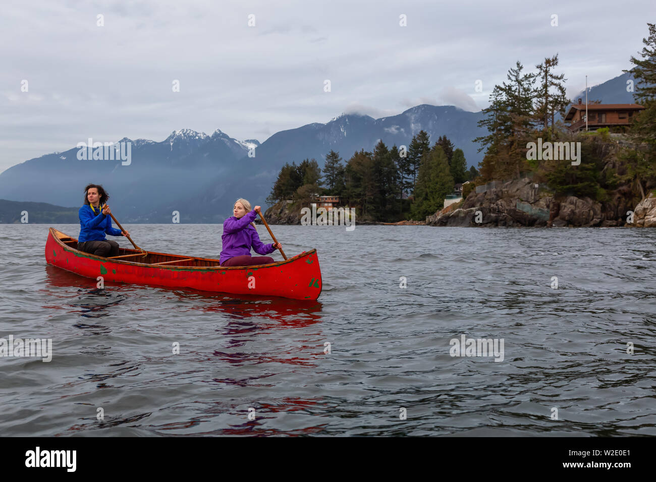 Couple adventurous female friends on a red canoe are paddling in the ...
