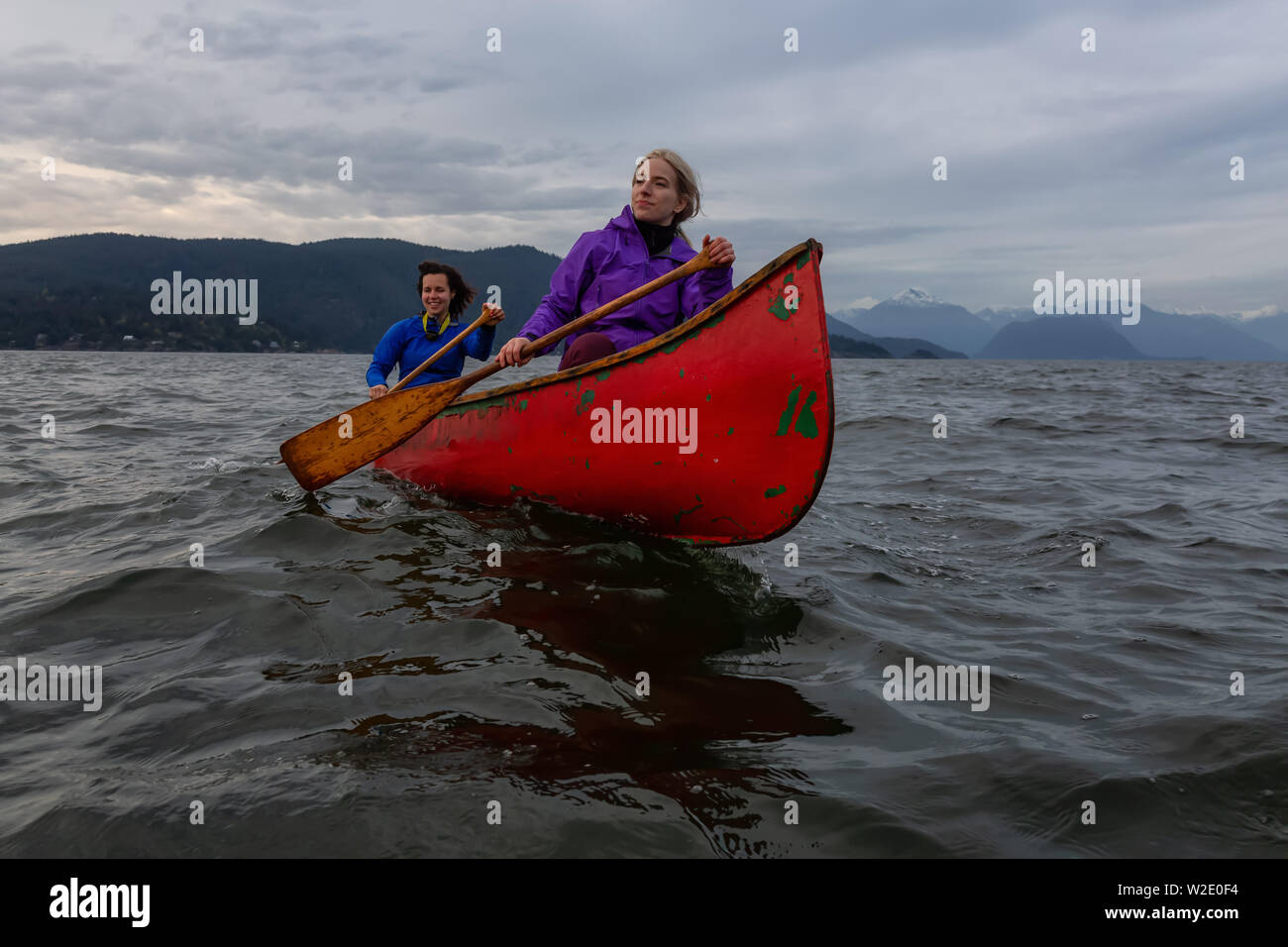 Couple adventurous female friends on a red canoe are paddling in the ...