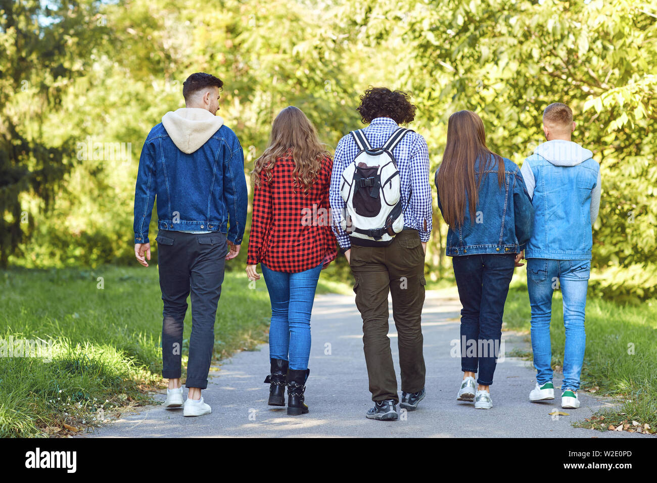 Back view. Friends walk in the park in spring autumn Stock Photo - Alamy
