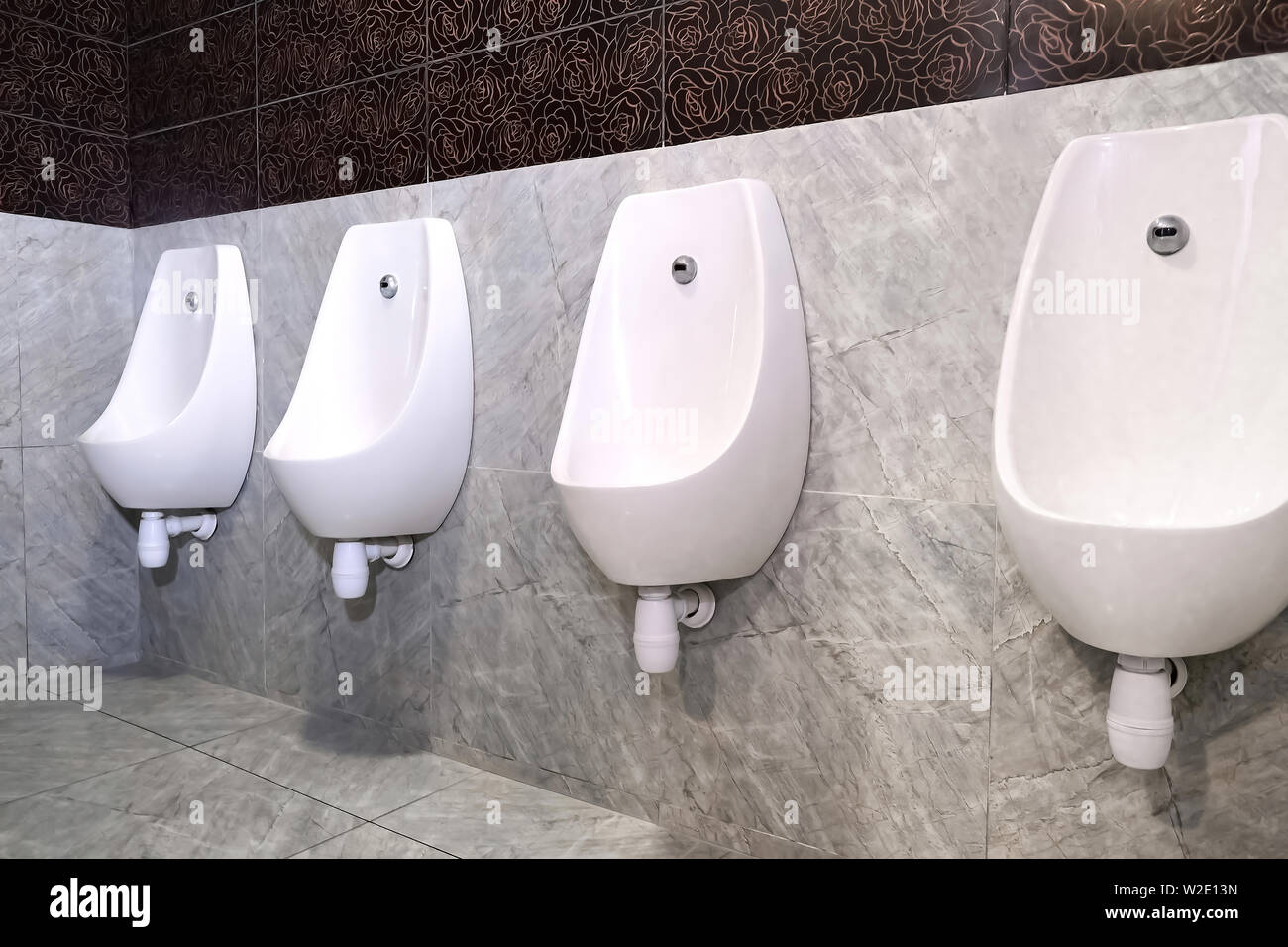 Urinals in the toilet on the wall hanging in a row Stock Photo - Alamy