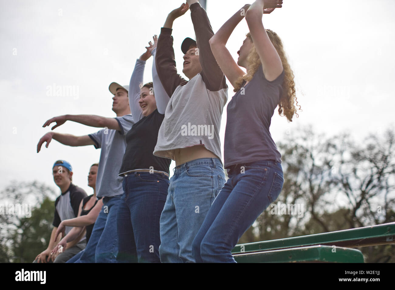 Friends doing mexican wave on bleachers Stock Photo - Alamy