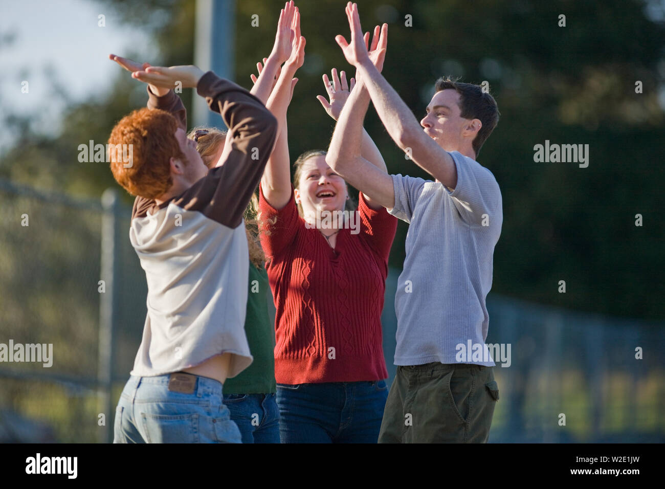 Four excited teenagers giving each other a high five in a park Stock ...