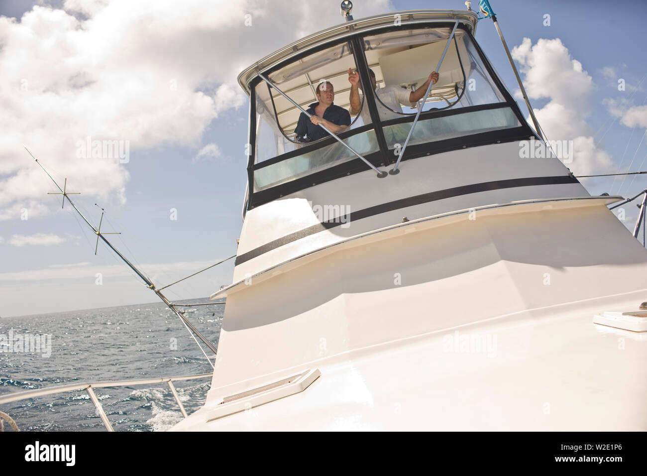 Two men standing in the cockpit of a boat out in the ocean Stock Photo ...