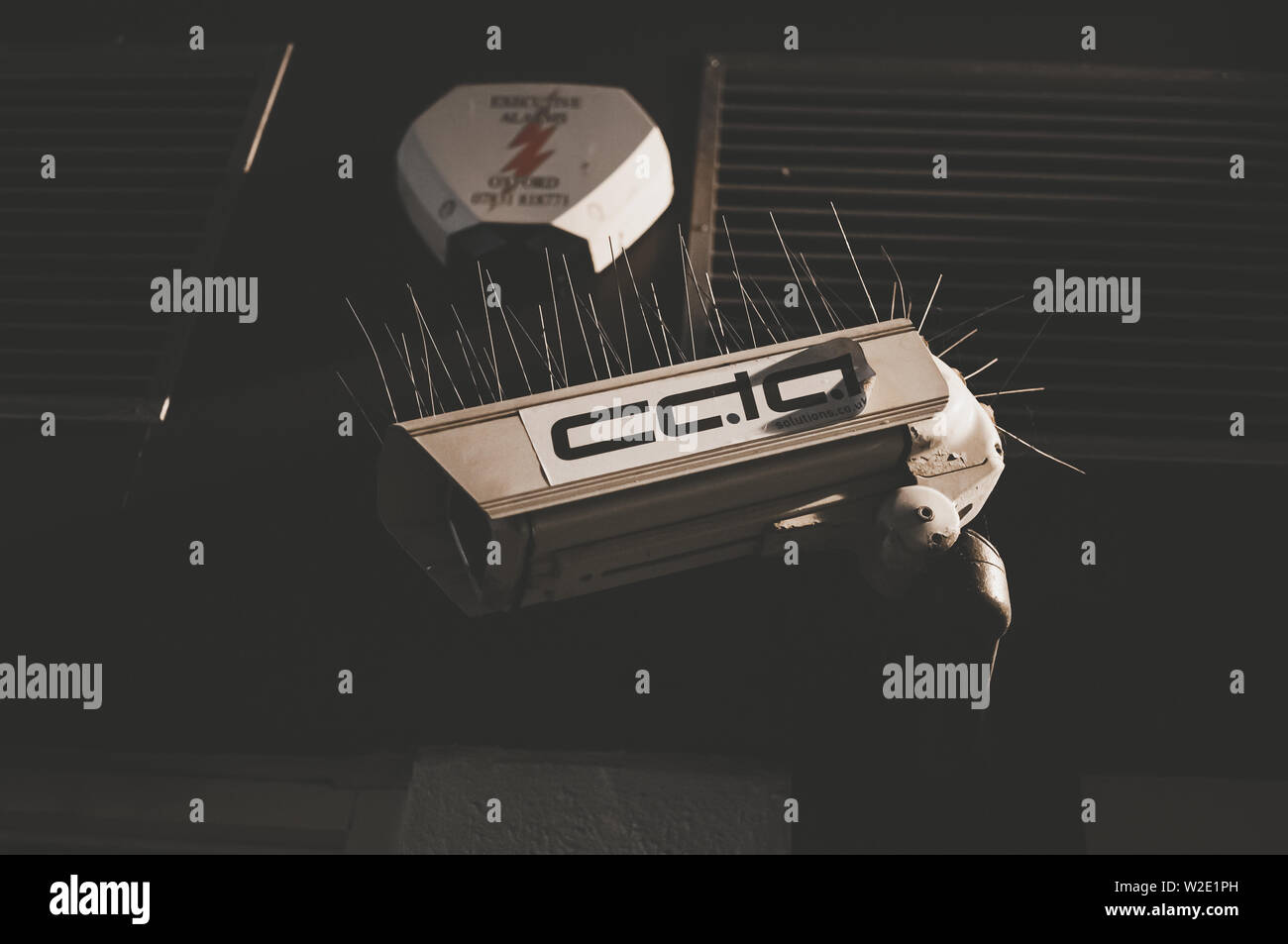 A CCTV camera with bird deterrent spikes attached and house alarm in ...