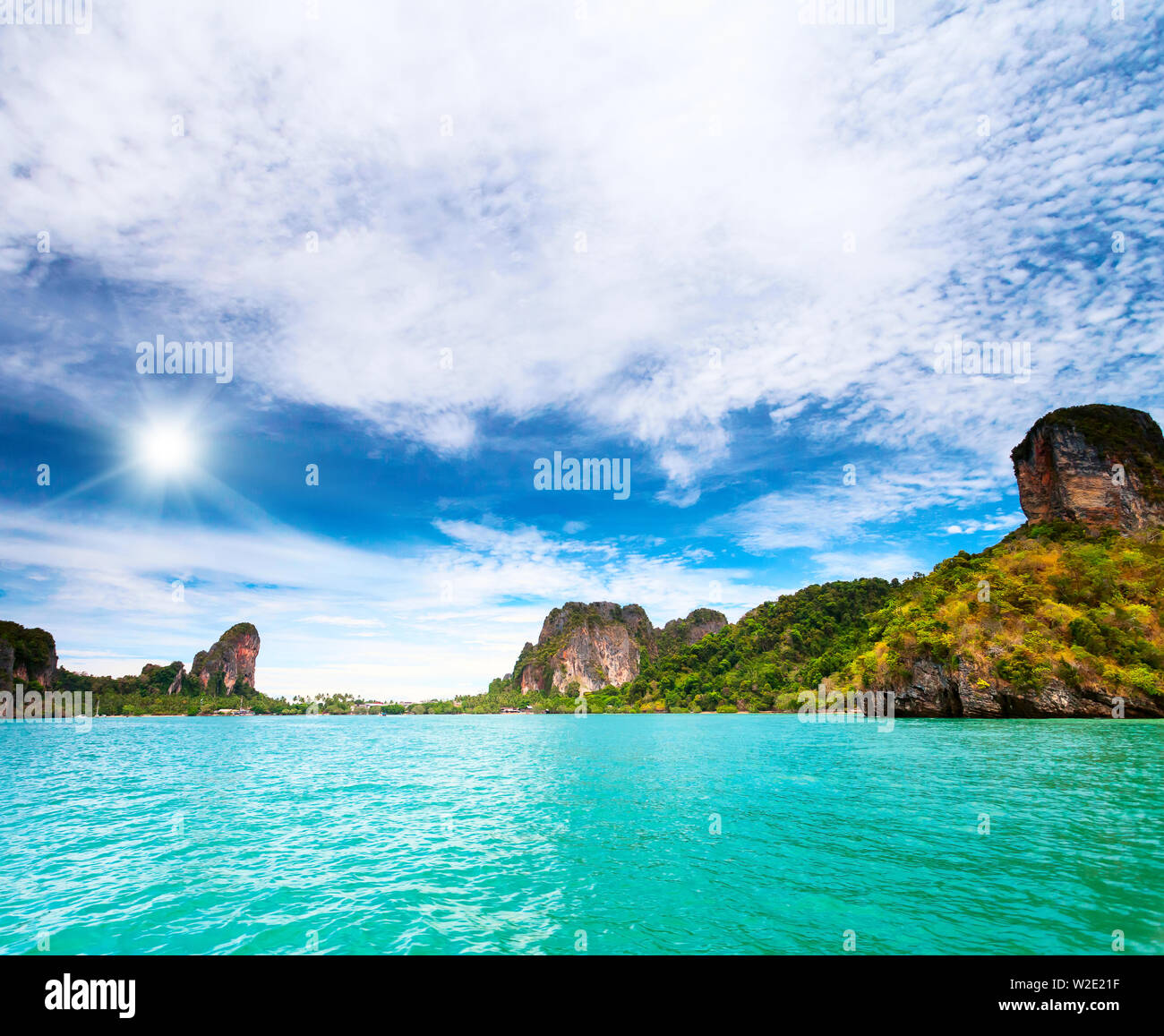 Big rocks on bank with trees and bushes. clear sea water and blue sky ...