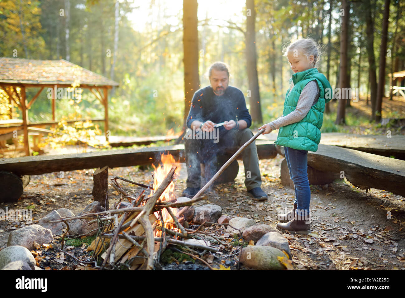 Cute young girl learning to start a bonfire. Father teaching her ...