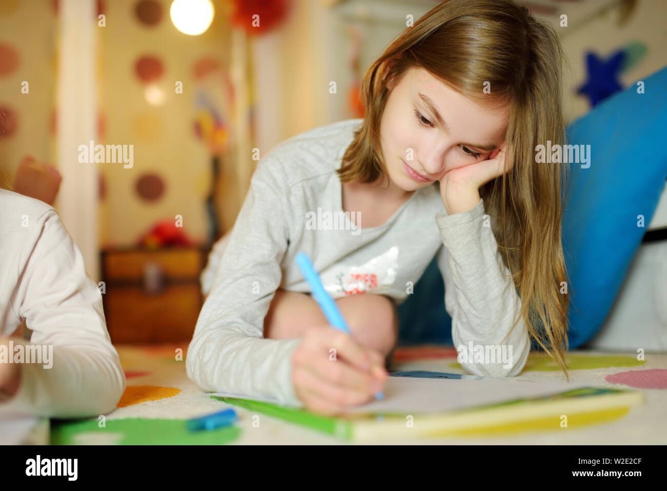 Two cute little sisters writing letters together at home. Older sister ...