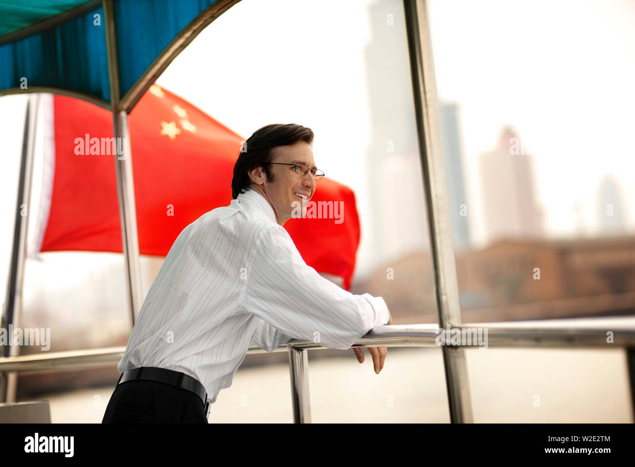 Smiling middle aged businessman leaning on a rail Stock Photo - Alamy