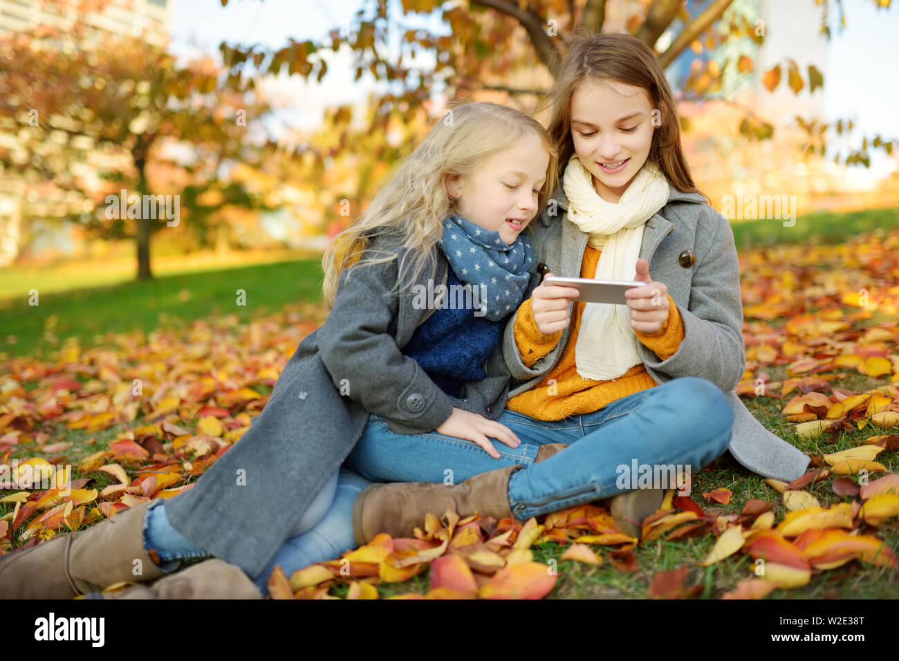 Two cute young sisters having fun on beautiful autumn day. Happy ...