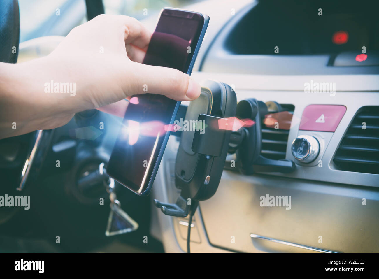 Modern wireless smartphone charging in a car with a hand putting a ...