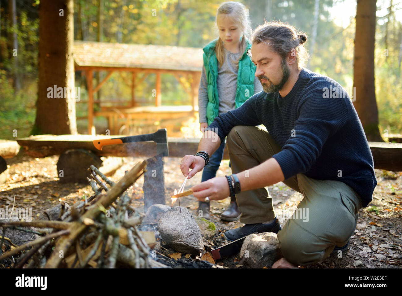 Cute young girl learning to start a bonfire. Father teaching her ...