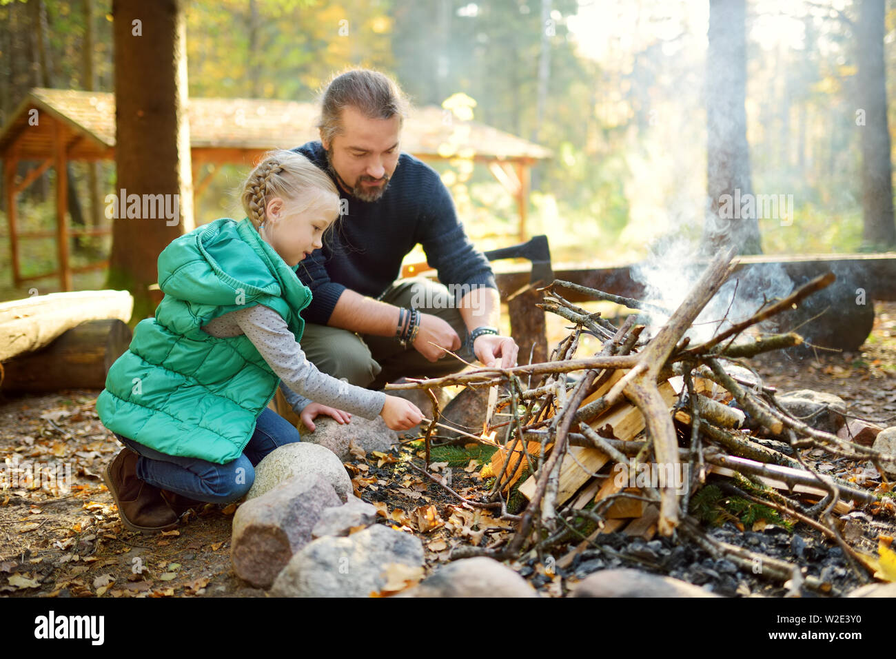 Cute young girl learning to start a bonfire. Father teaching her ...