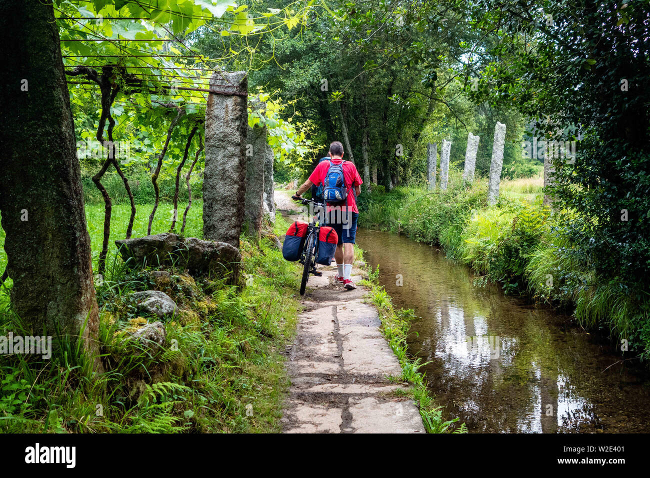 Portugal. 20th June, 2019. A pilgrim walks with his bike crossing a ...