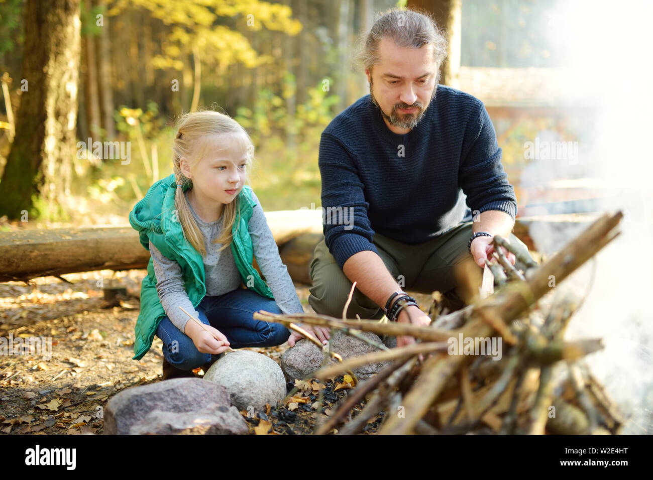 Cute young girl learning to start a bonfire. Father teaching her ...