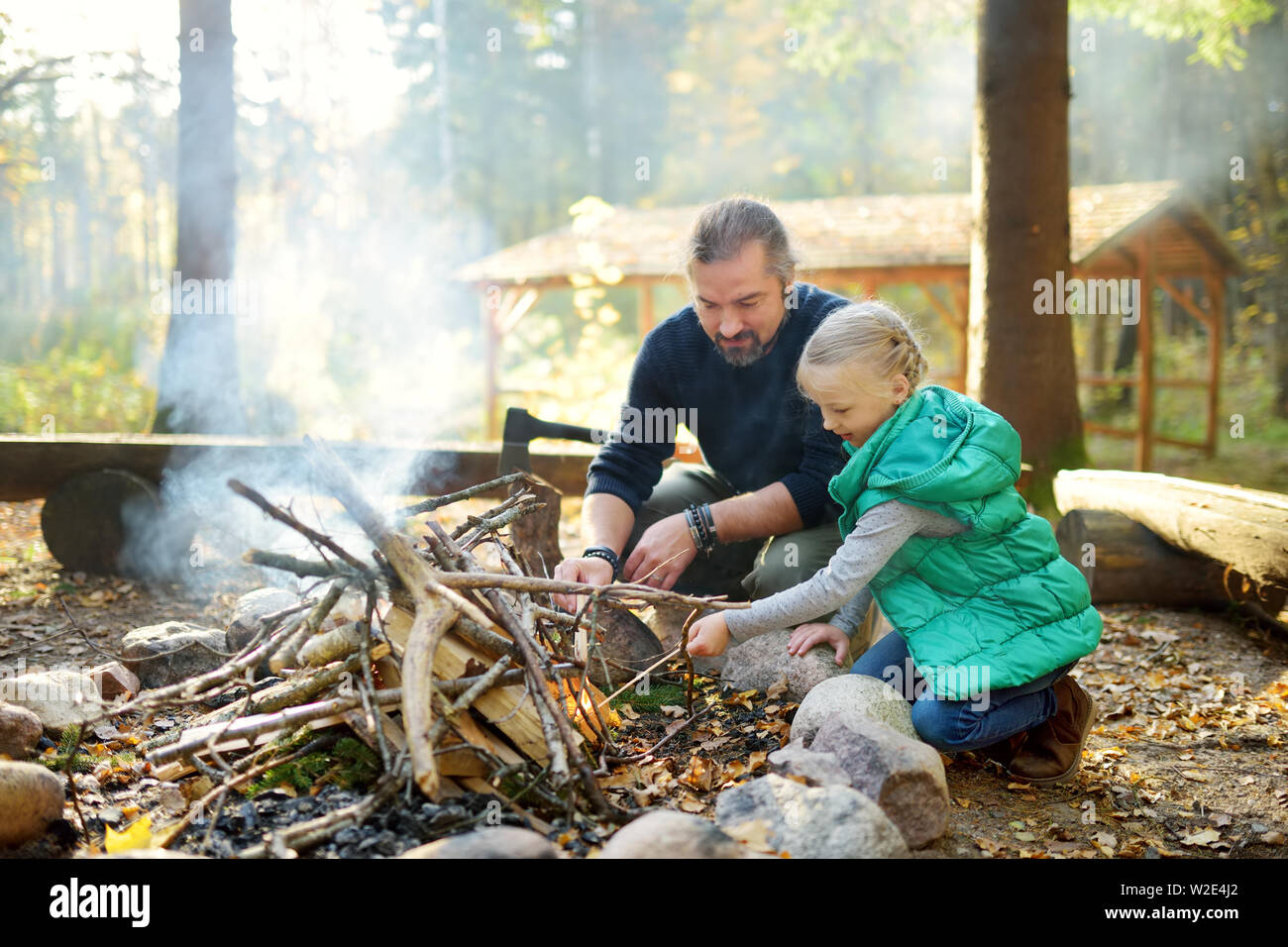 Cute young girl learning to start a bonfire. Father teaching her ...