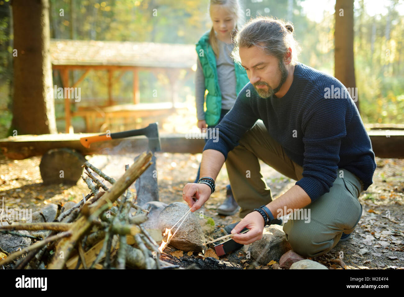 Cute young girl learning to start a bonfire. Father teaching her ...