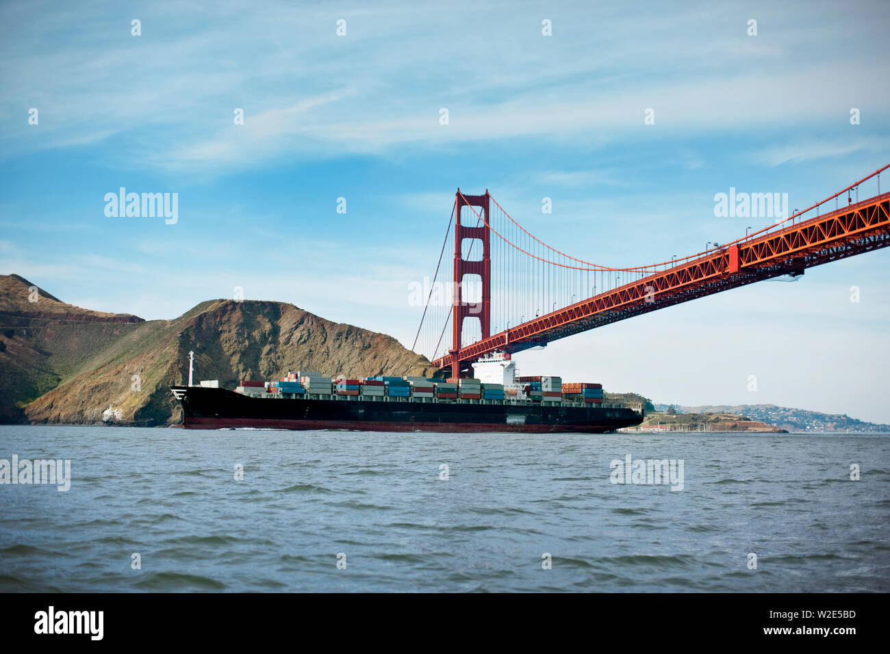 A cargo ship passing under a suspension bridge Stock Photo - Alamy