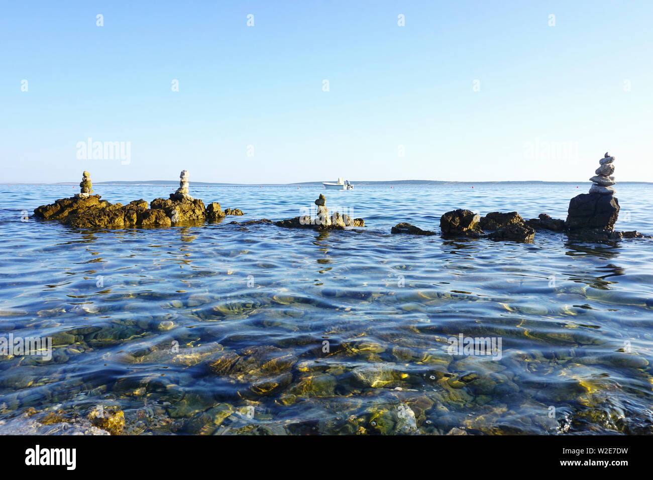 Beautiful seascape with stacked stones in the clear blue sea water with ...