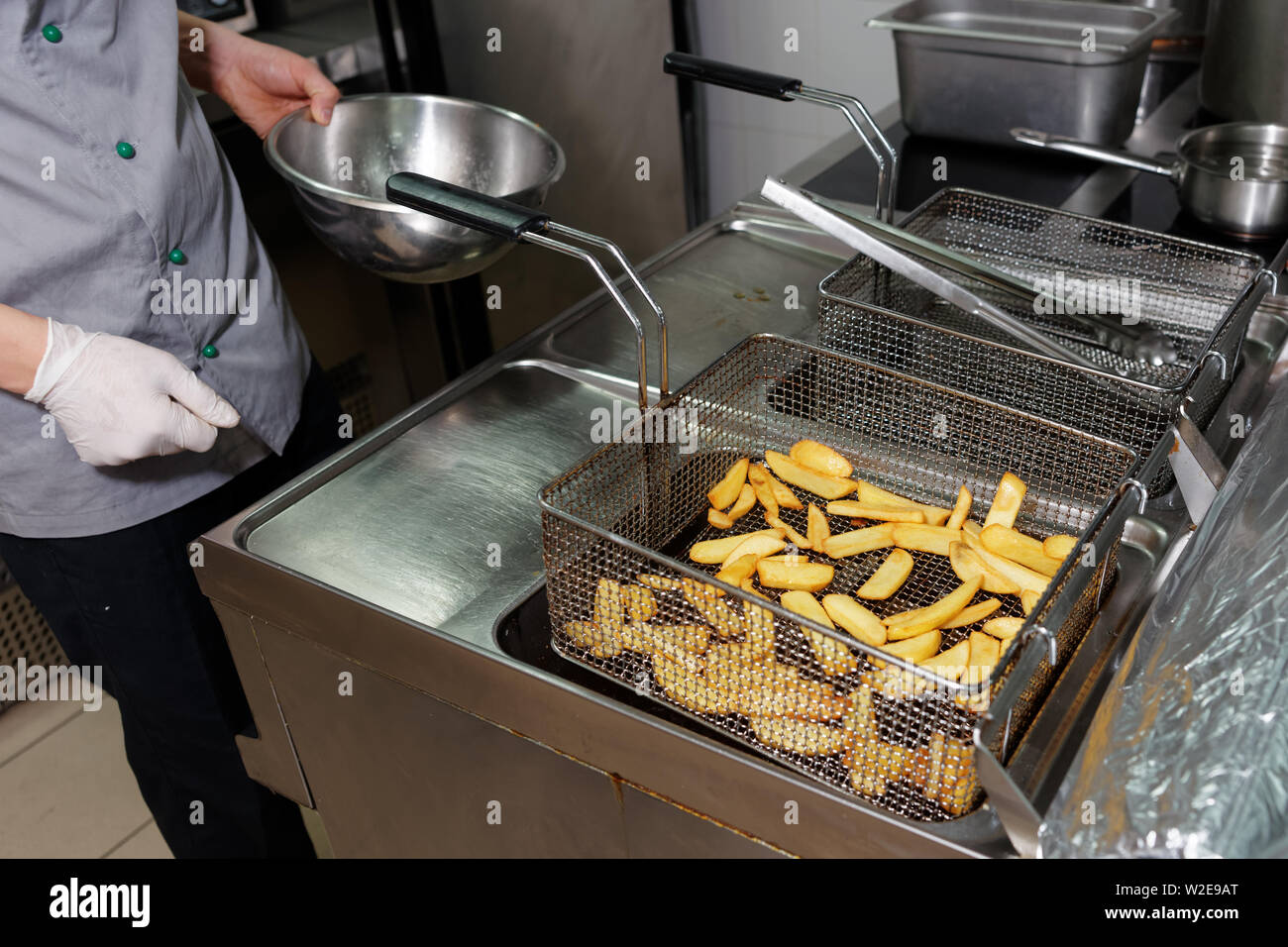 Chef is cooking french fries at commercial kitchen Stock Photo - Alamy