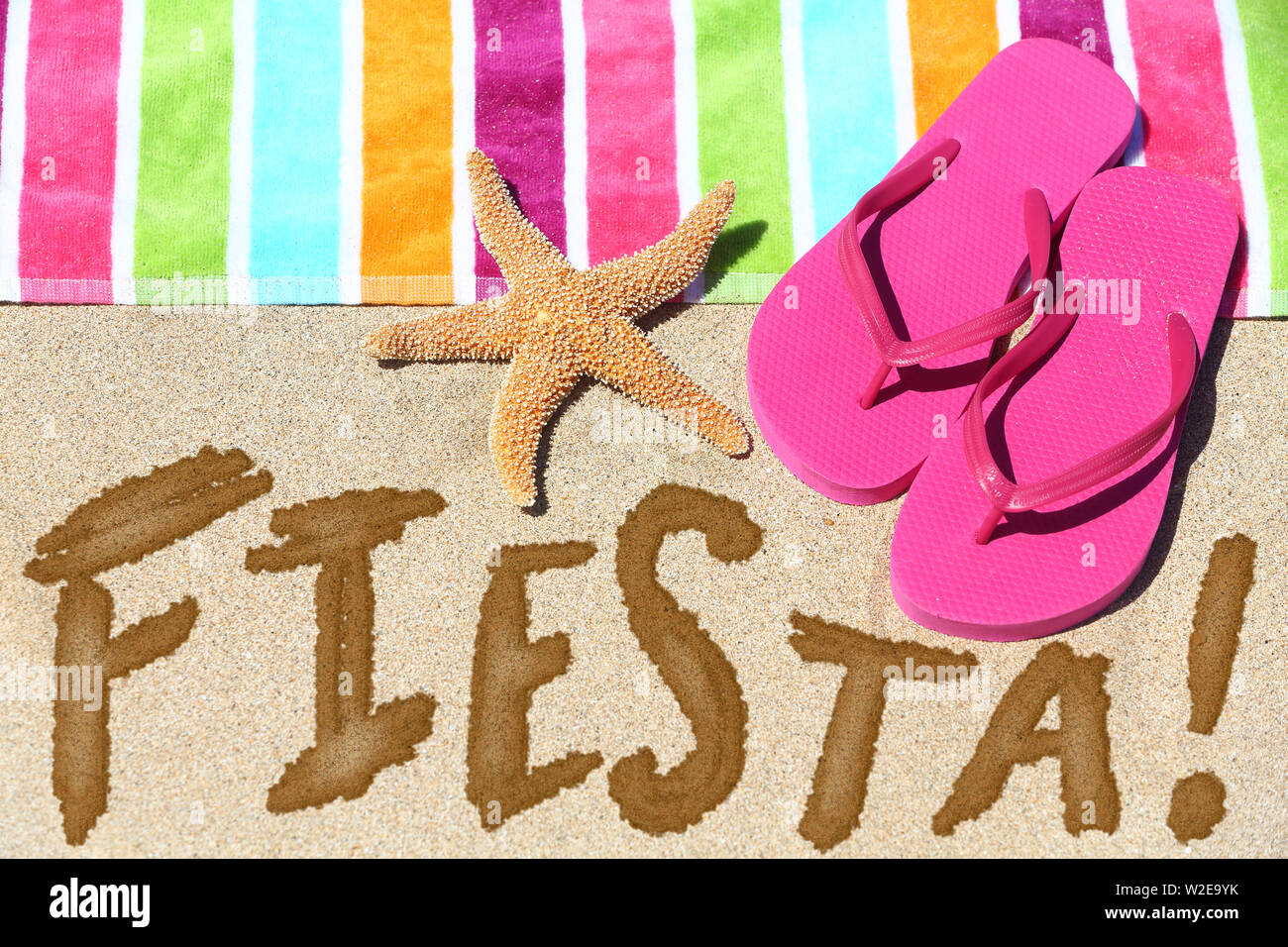 Beach party fiesta travel fun concept. FIESTA written in sand with ...