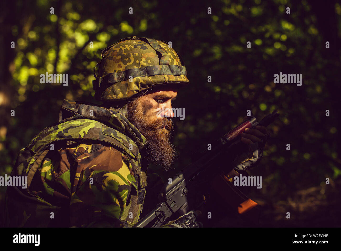 Young soldier with sad bearded face in military helmet and camouflage ...