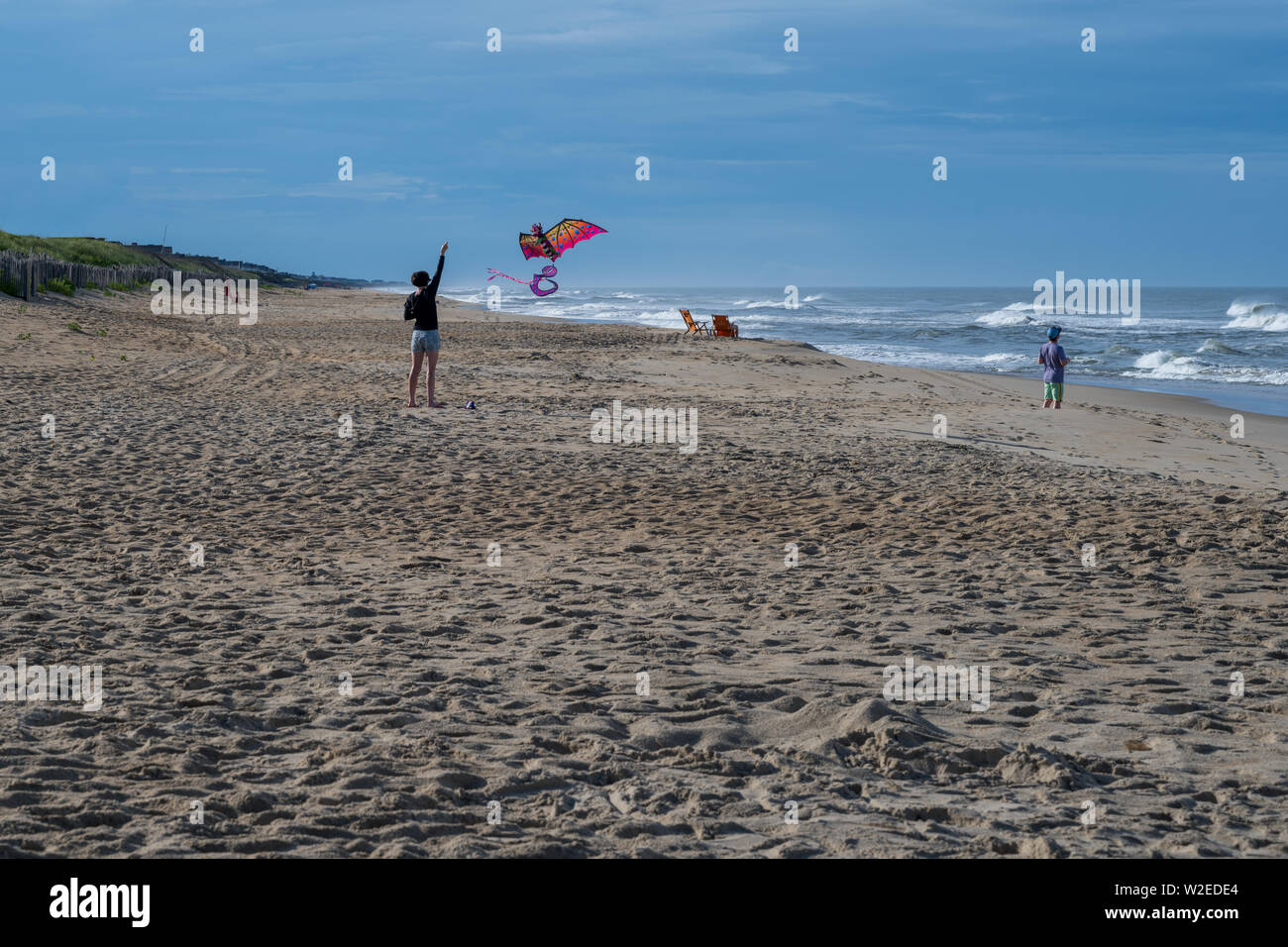 Duck, North Carolina, USA -- June 10, 2019. A young lady flies a kite ...