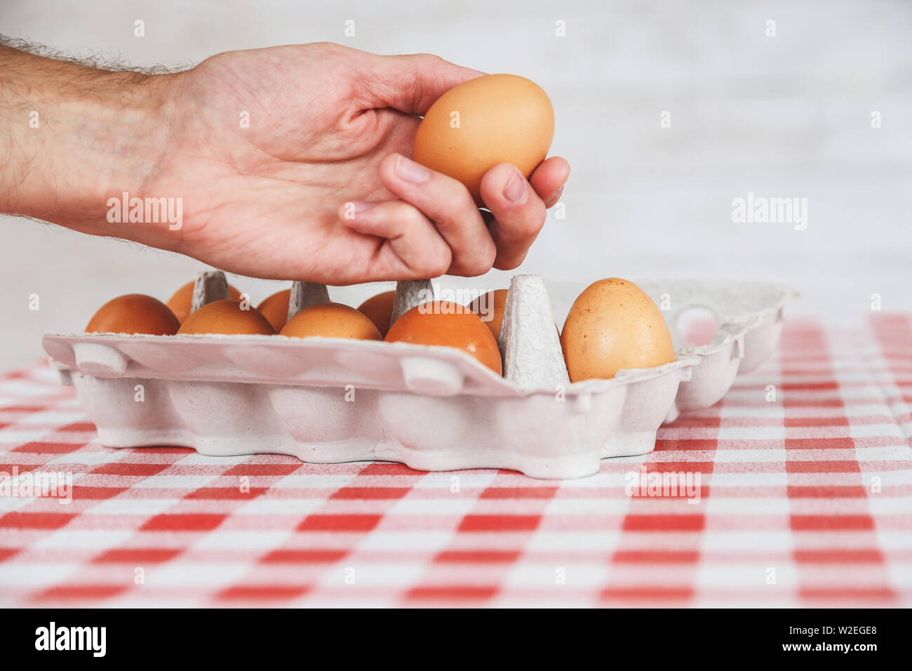 Man taking egg from cardboard egg box Stock Photo - Alamy
