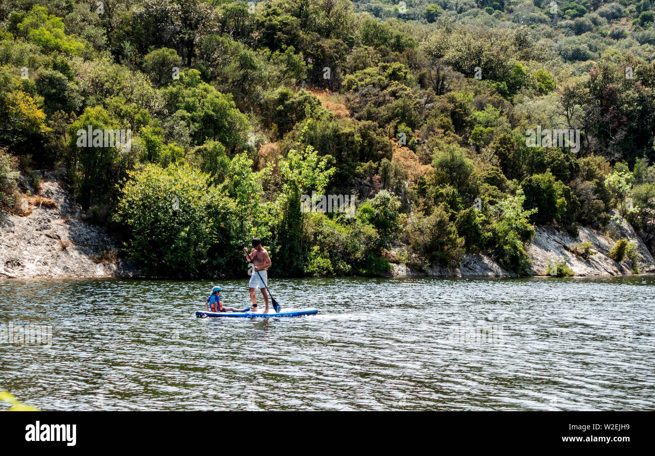 Man teaching a little boy how to use a Paddle Board on a lake Stock ...