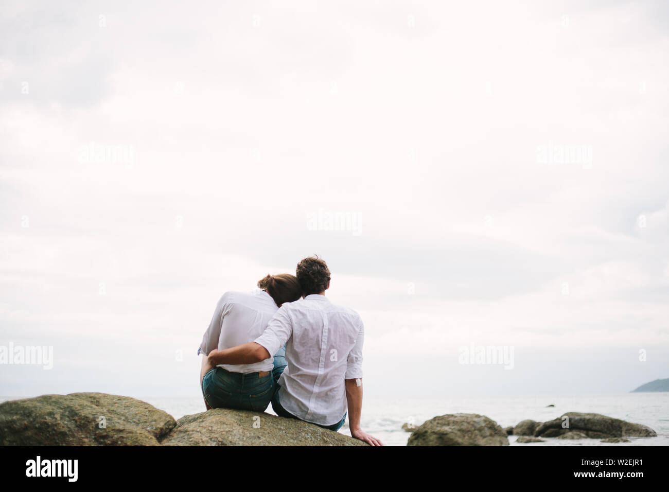 A man hugs a woman. They sit and look at the sea. Solitude together ...
