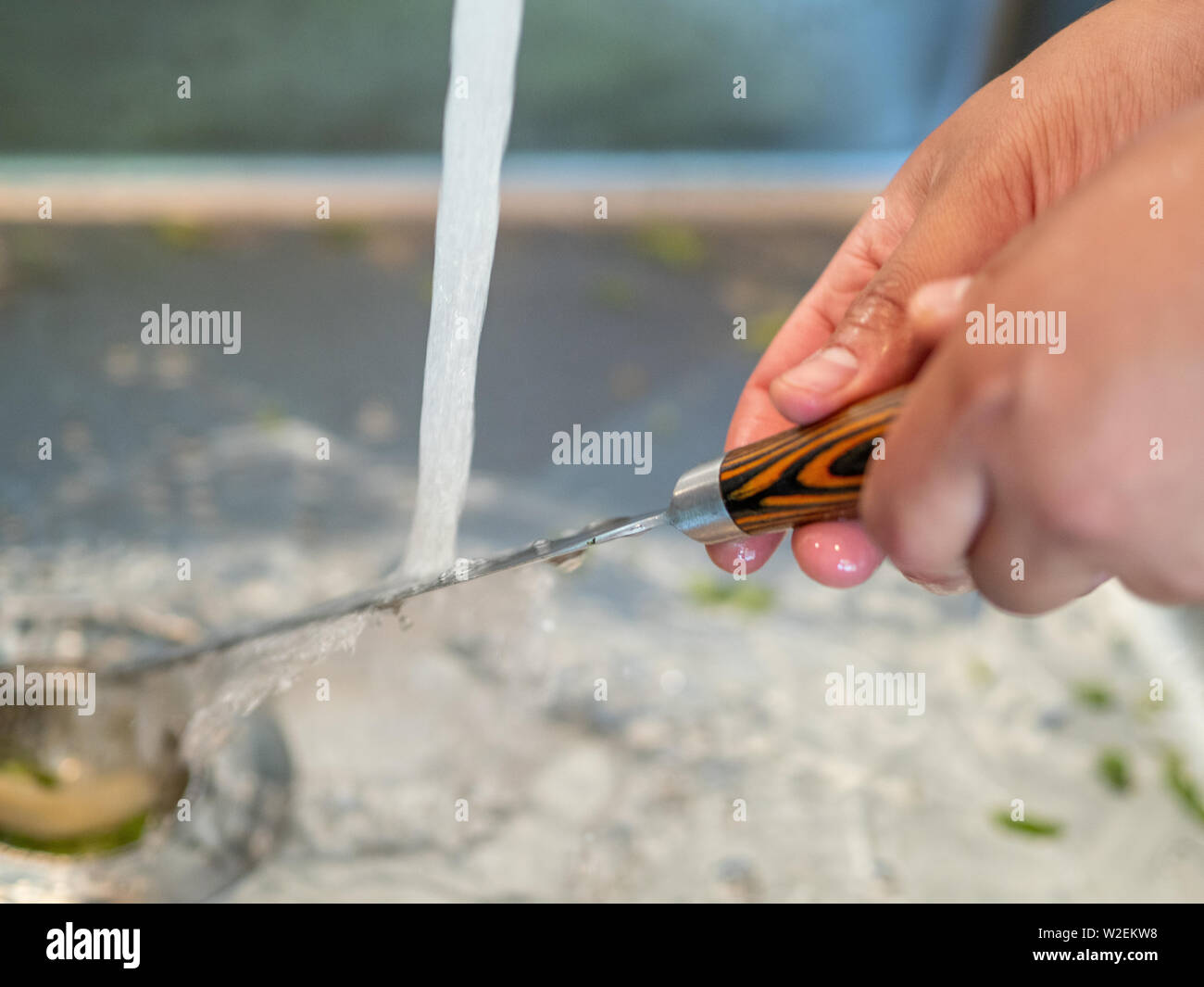 Man's hands washing under the tap a kitchen knife Stock Photo - Alamy