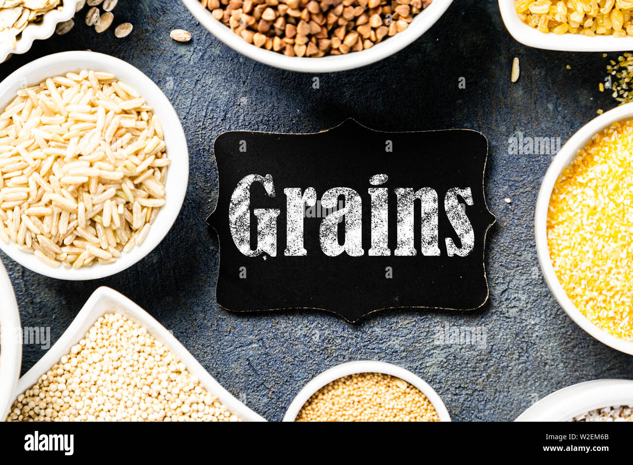 Selection of whole grains in white bowls - rice, oats, buckwheat ...