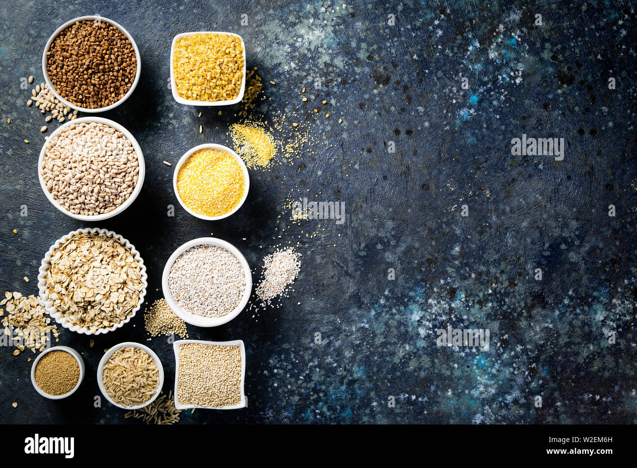 Selection of whole grains in white bowls - rice, oats, buckwheat ...
