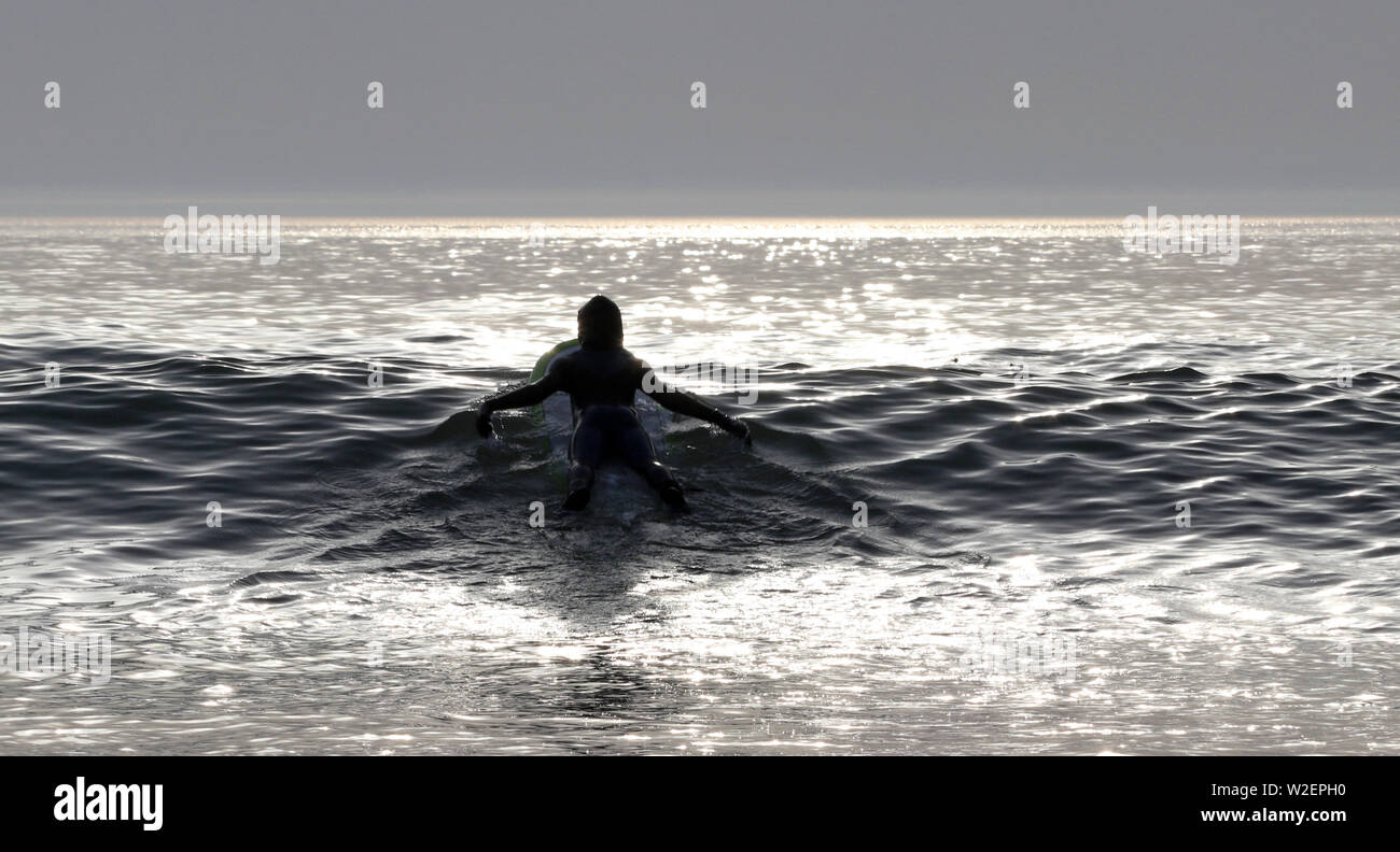 single surfer laying on his board enjoying the peace of the moment ...