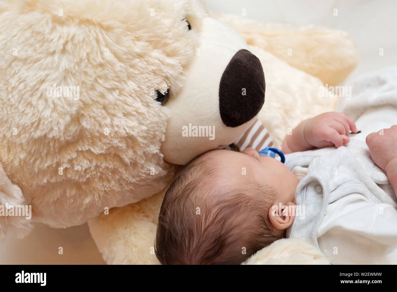 Peaceful newborn sleeping with giant fluffy teddy bear Stock Photo - Alamy