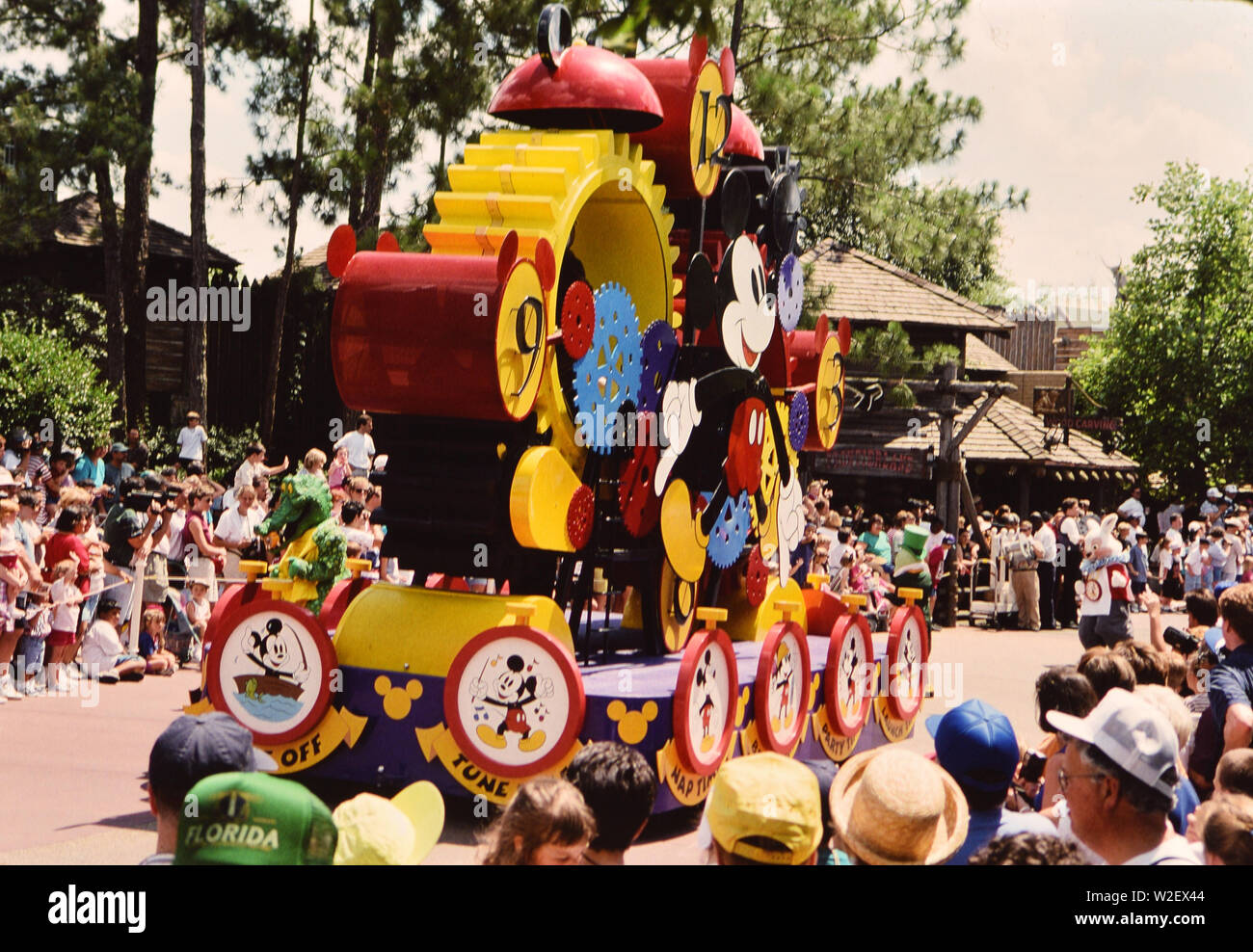 Families and children watching a Mickey Mouse clock float in a parade ...