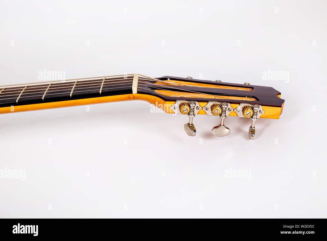 Tuning pegs on wooden machine head of six strings guitar on white ...