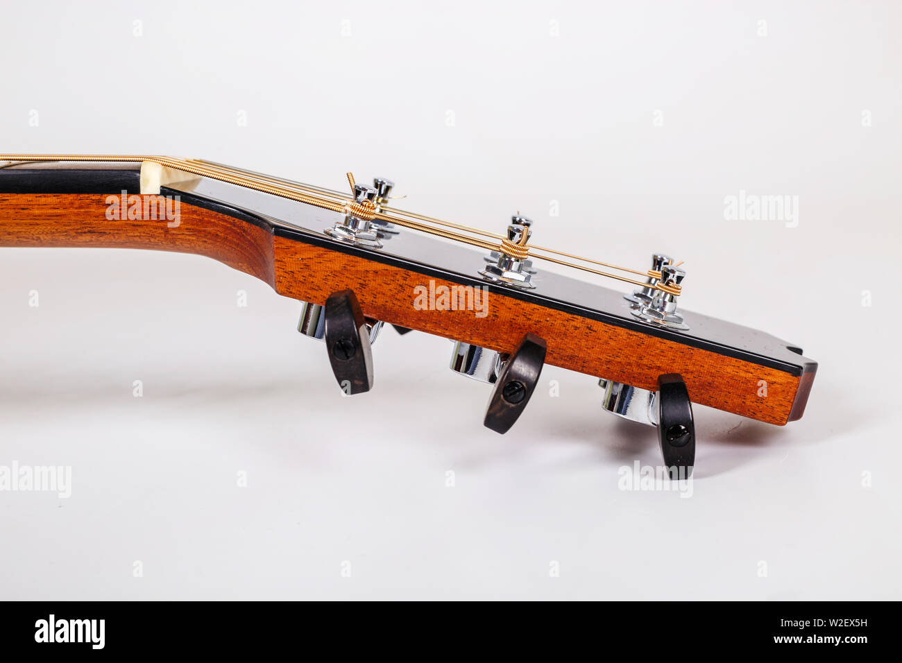 Tuning pegs on wooden machine head of six strings guitar on white ...