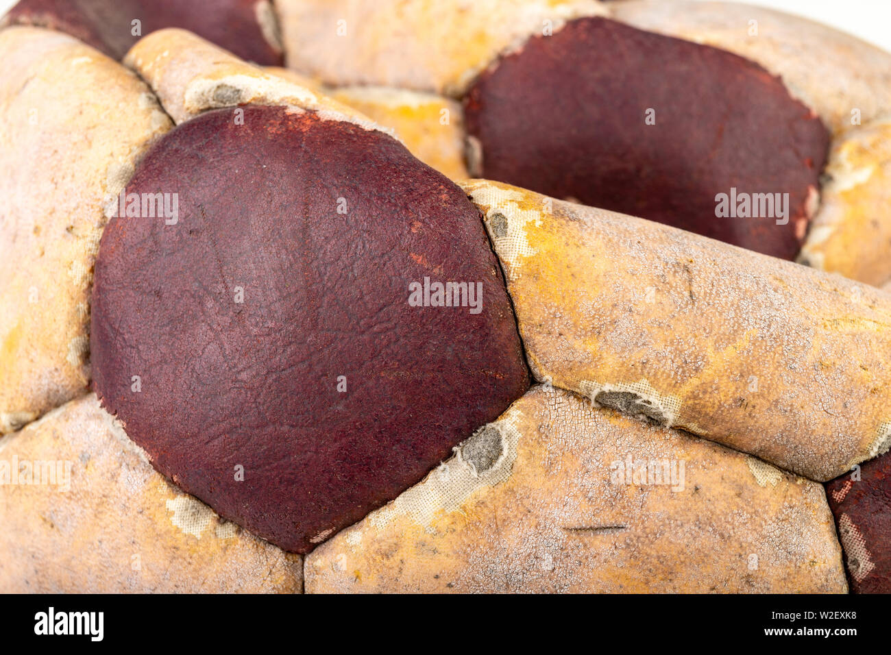 Close-up of an old soccer ball on the leg on a white table. Leather and ...